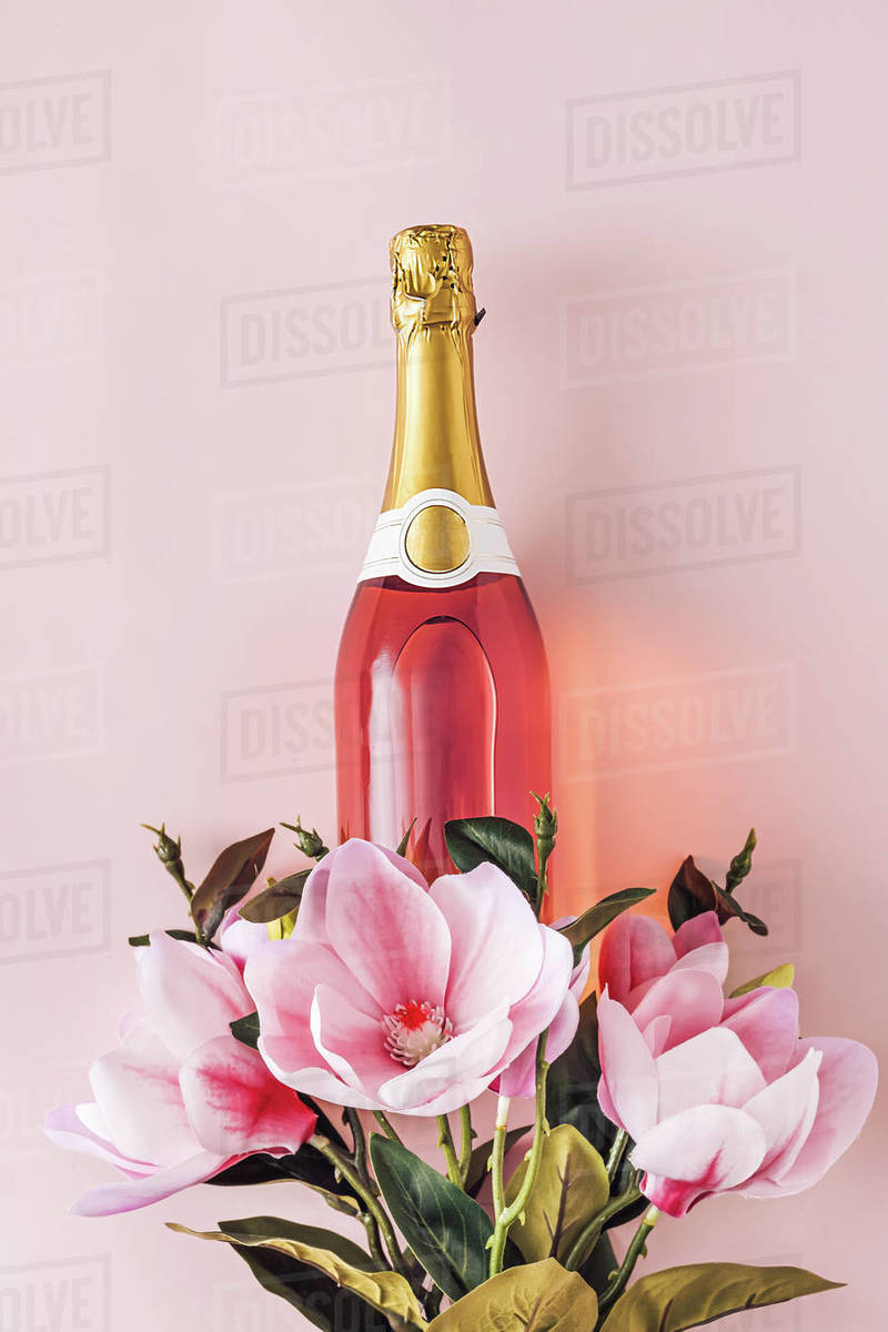 Full bottle of pink champagne with fresh flowers symbolic of love and ...