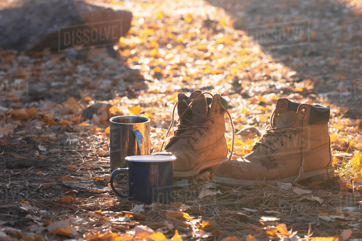A camping aesthetics. cups with tea and boots in the dawn light - Stock Photo - Dissolve