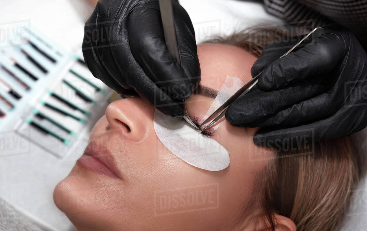Woman with long eyelashes in a beauty salon. Eyelash extension process ...