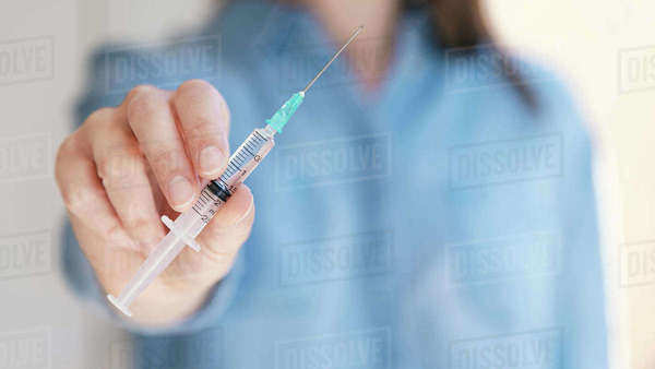 Woman holding medical injection syringe in her outstretched hand ...