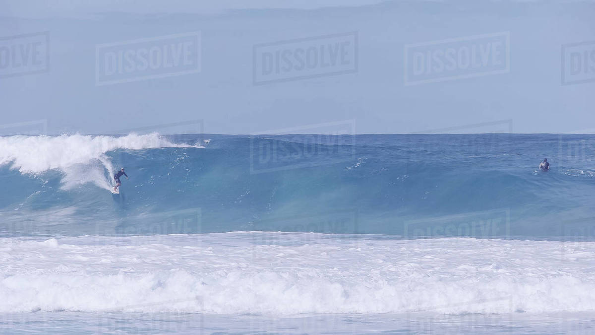 a wide view of surfers at pipeline surf break in hawai on the island of ...