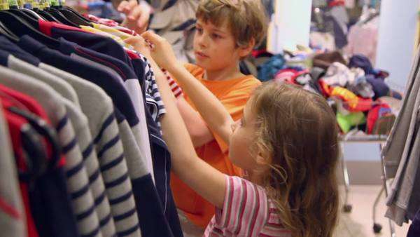Two kids boy with little girl take and watch shirts in clothes shop ...