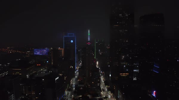 Backwards reveal of illuminated streets and modern tall buildings ...