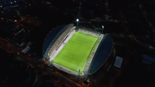 Fly around football stadium at night. High angle view of brightly lit ...