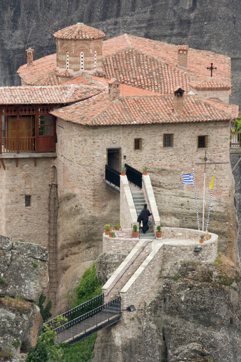 Greece, Meteora. Greek Orthodox priest walking up stairs to Saint ...