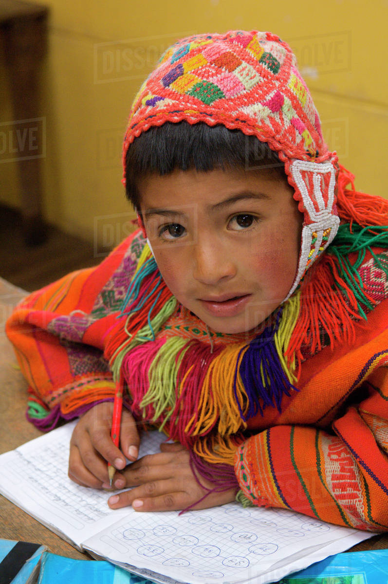Peru, Huilloc, Portrait of boy in native dress writing in school ...