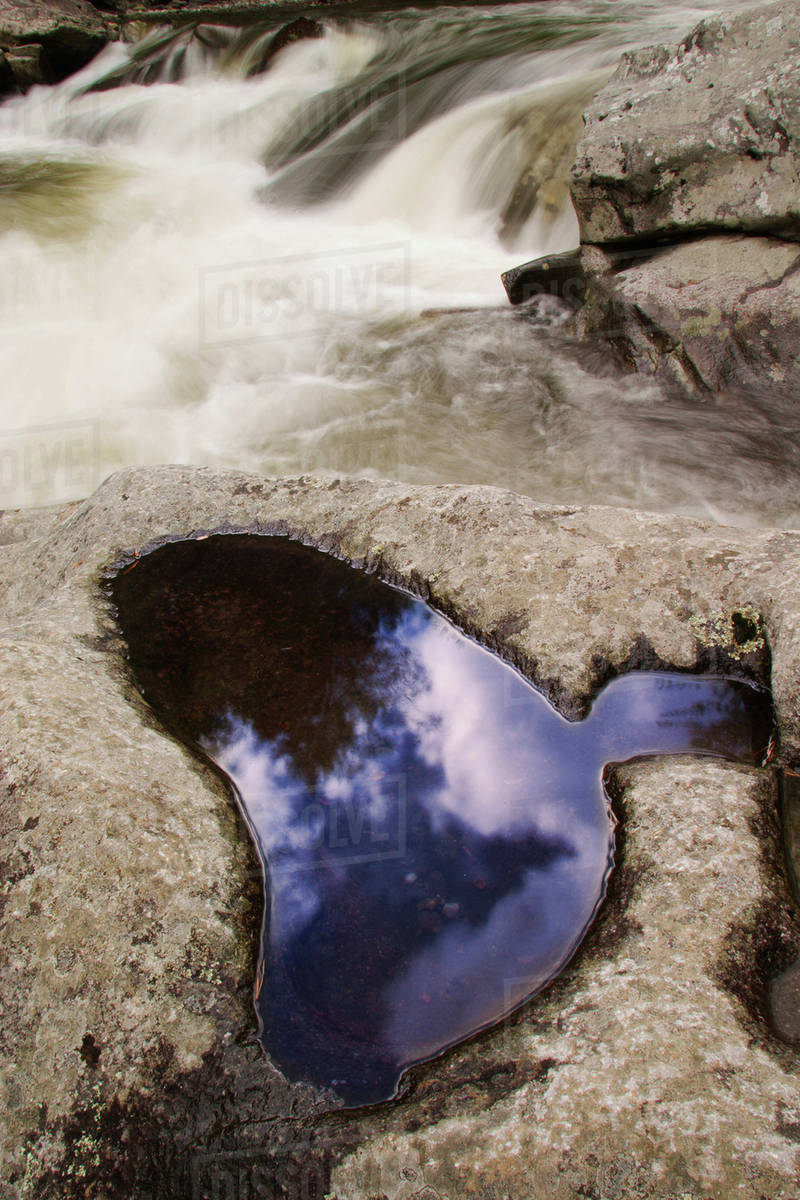 Pool of rainwater on boulder reflecting image of sky, Little River ...