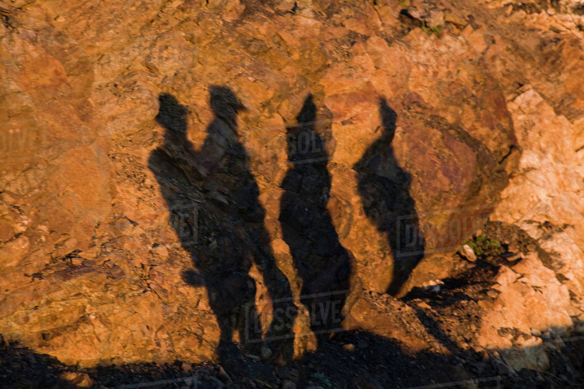 USA, Washington, Mount Baker. Four hikers' shadows project onto boulder ...