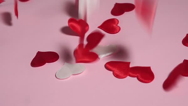 Hearts fall on a pink background. confetti in the shape of hearts ...