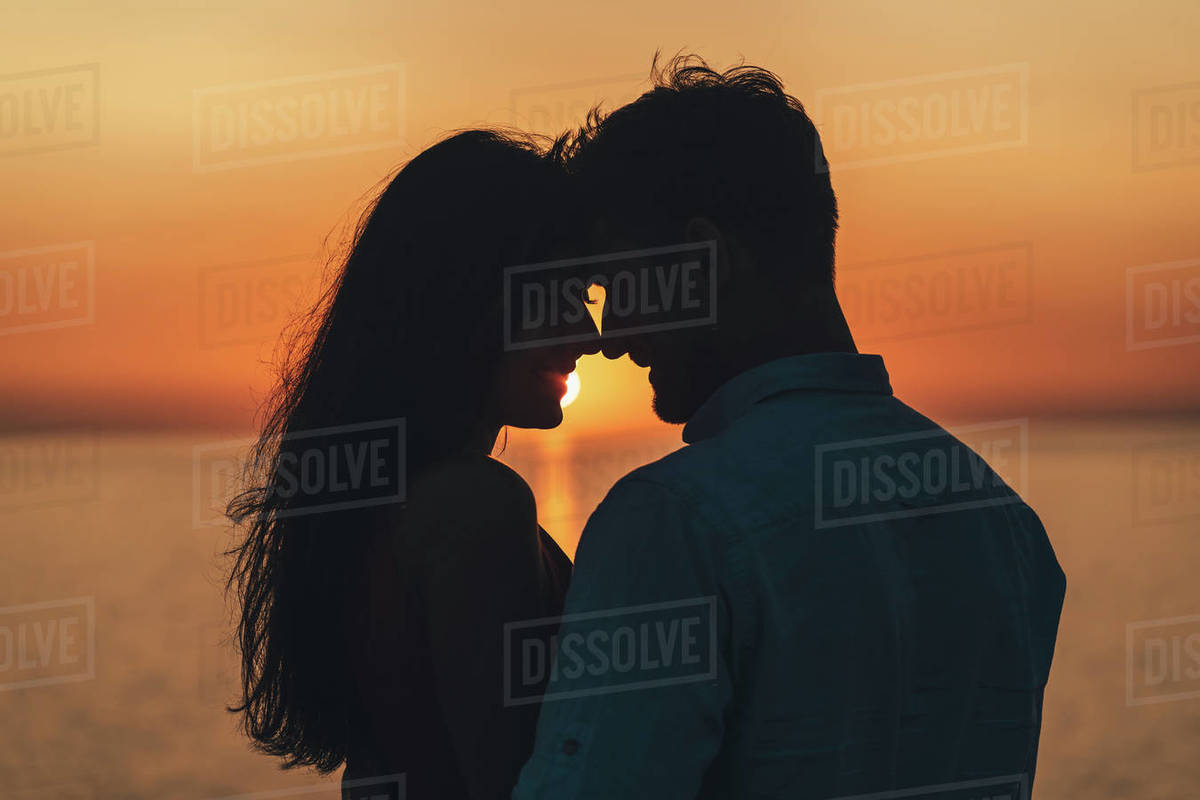 The two people standing on the sunset background - Stock Photo - Dissolve