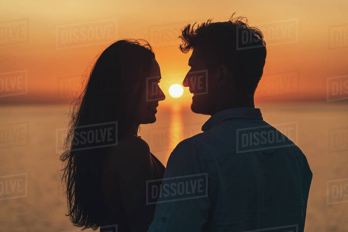 Two people standing on the sunset background - Stock Photo - Dissolve