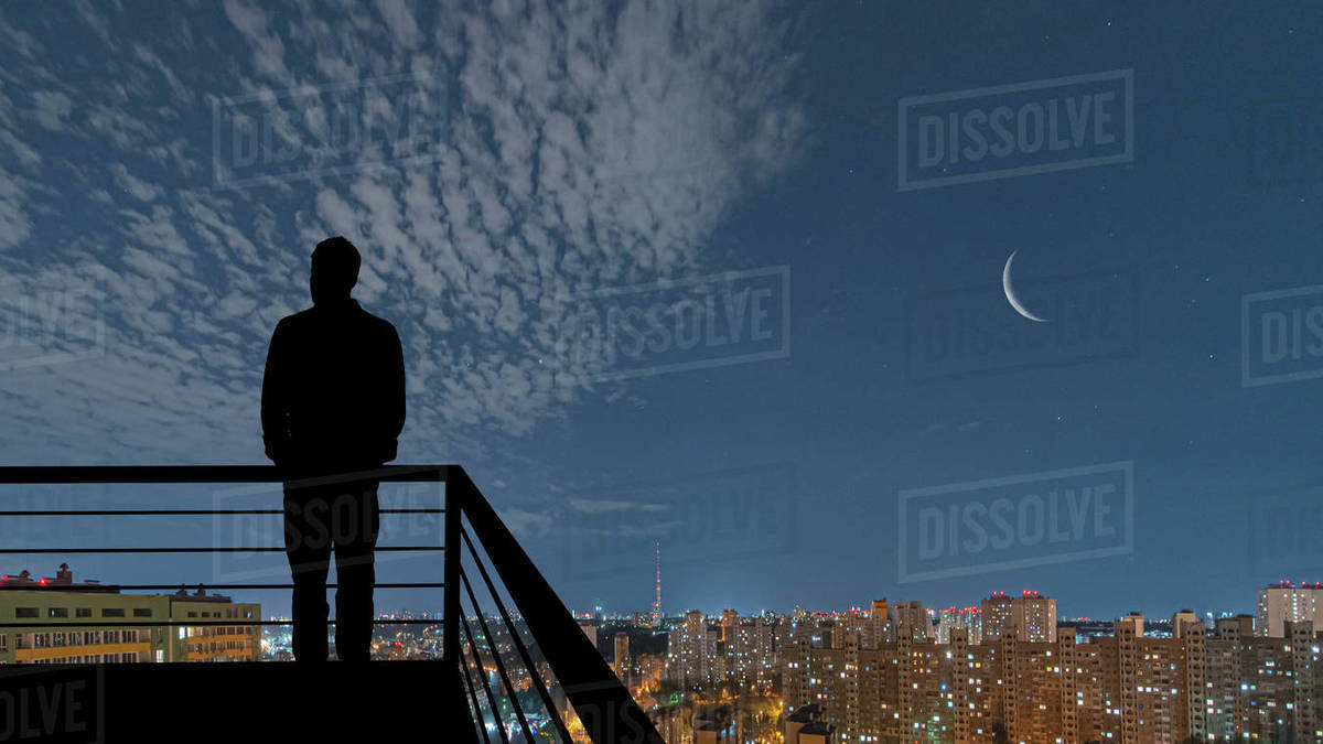 The man standing on the balcony on the night city background - Royalty ...