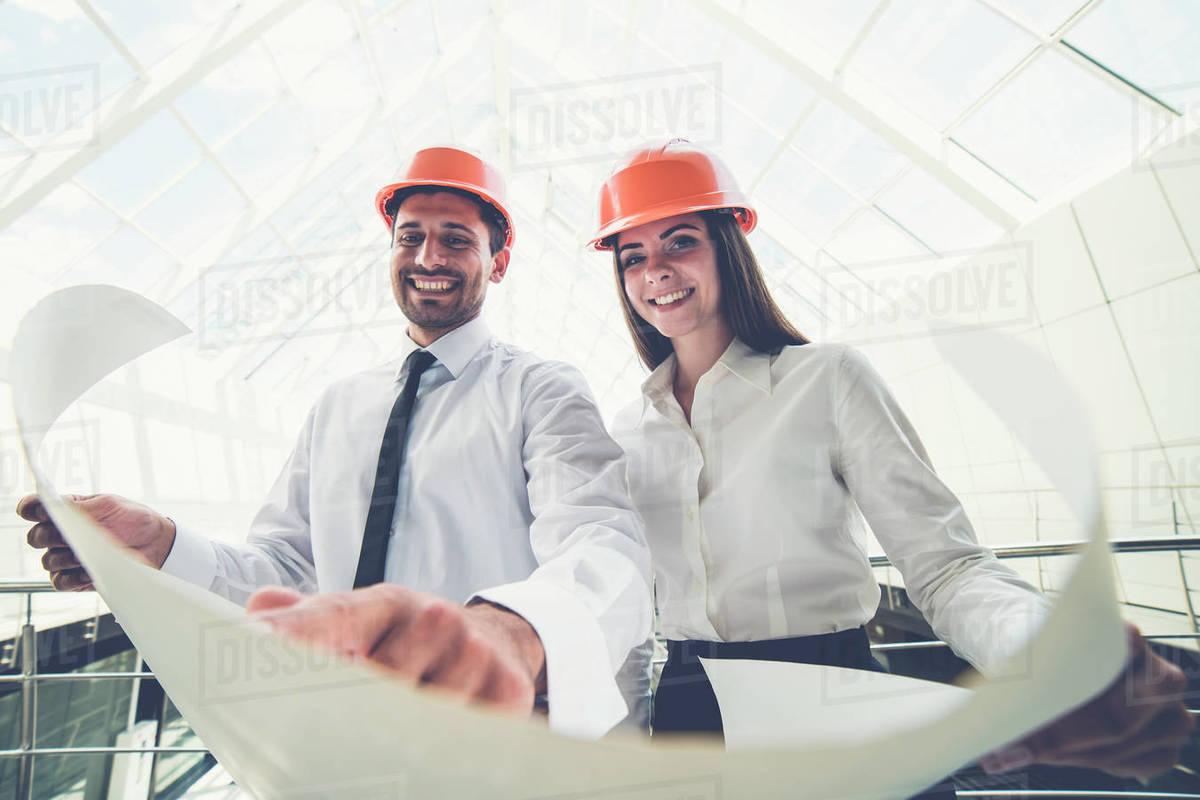 The two builders with helmets hold the project plan in the building ...