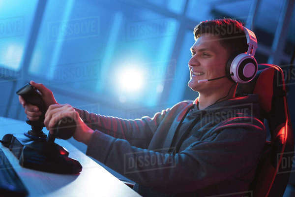 The gamer sitting at the table and playing video games in the neon room ...