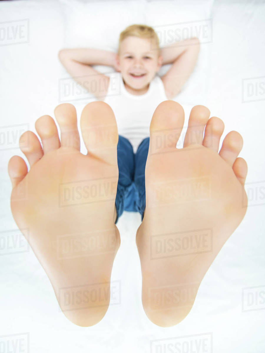 The happy boy lay on the bed and show legs. view from above - Royalty ...