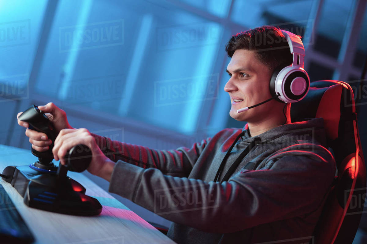 The gamer sitting at the table and playing video games in the neon room ...