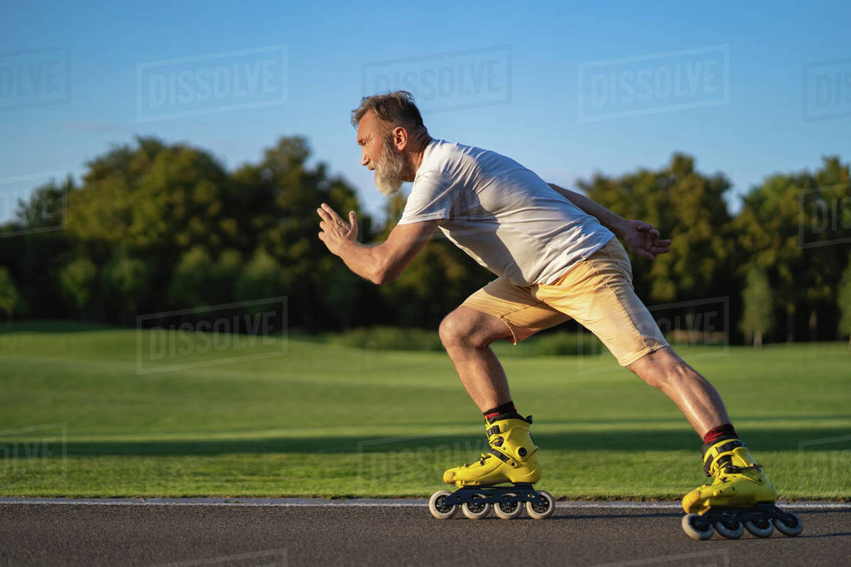 Elderly man rollerblading on the alley - Stock Photo - Dissolve