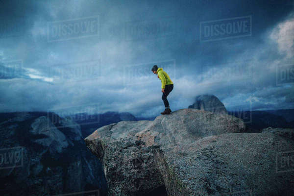 Mid adult man standing at top of mountain peering over edge, Yosemite ...