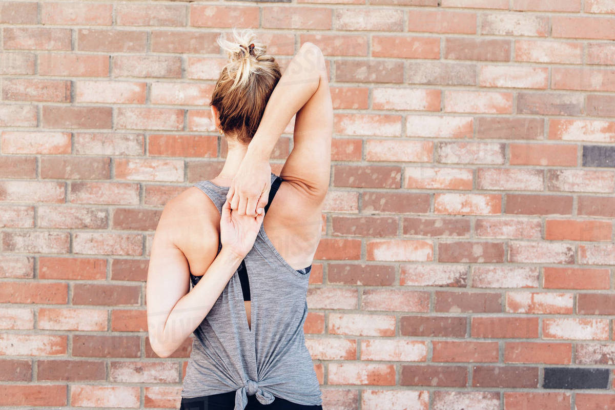 Rear view of woman, arms behind back stretching - Royalty-free Stock ...