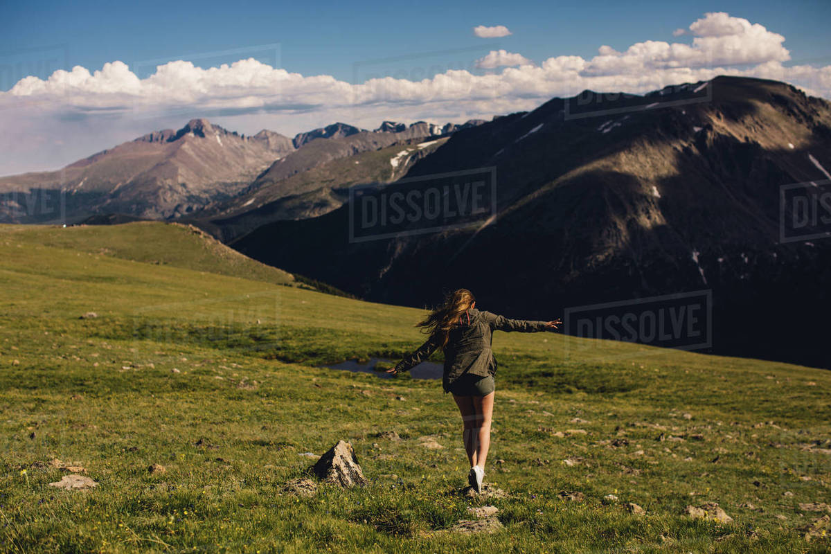 Woman balancing on rock by mountains, Rocky Mountain National Park ...