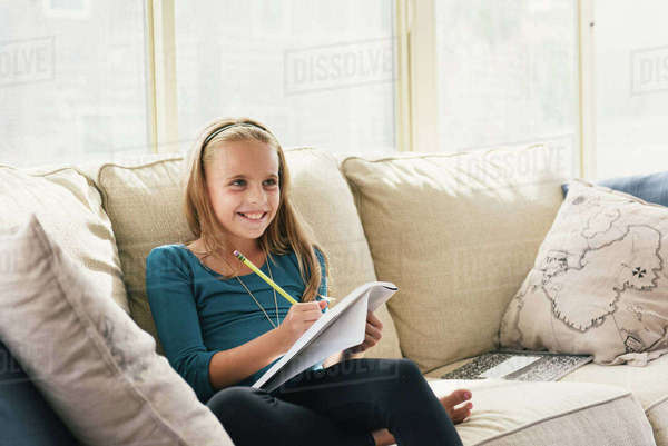 Girl sitting on sofa writing in notebook - Royalty-free Stock Photo ...