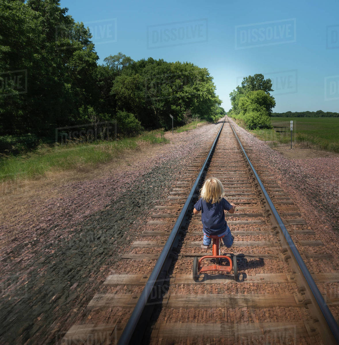 Rear view of boy riding tricycle on railway track - Royalty-free Stock ...