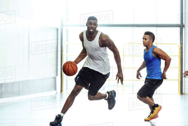 Male basketball players running with ball and defending on basketball ...