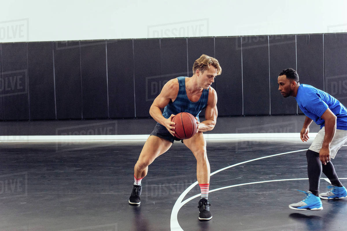 Two male basketball players practicing ball defence on basketball court ...