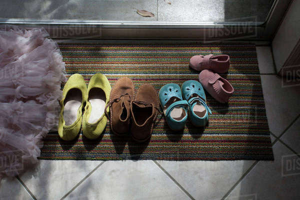 Different size shoes lined up on doormat - Stock Photo - Dissolve