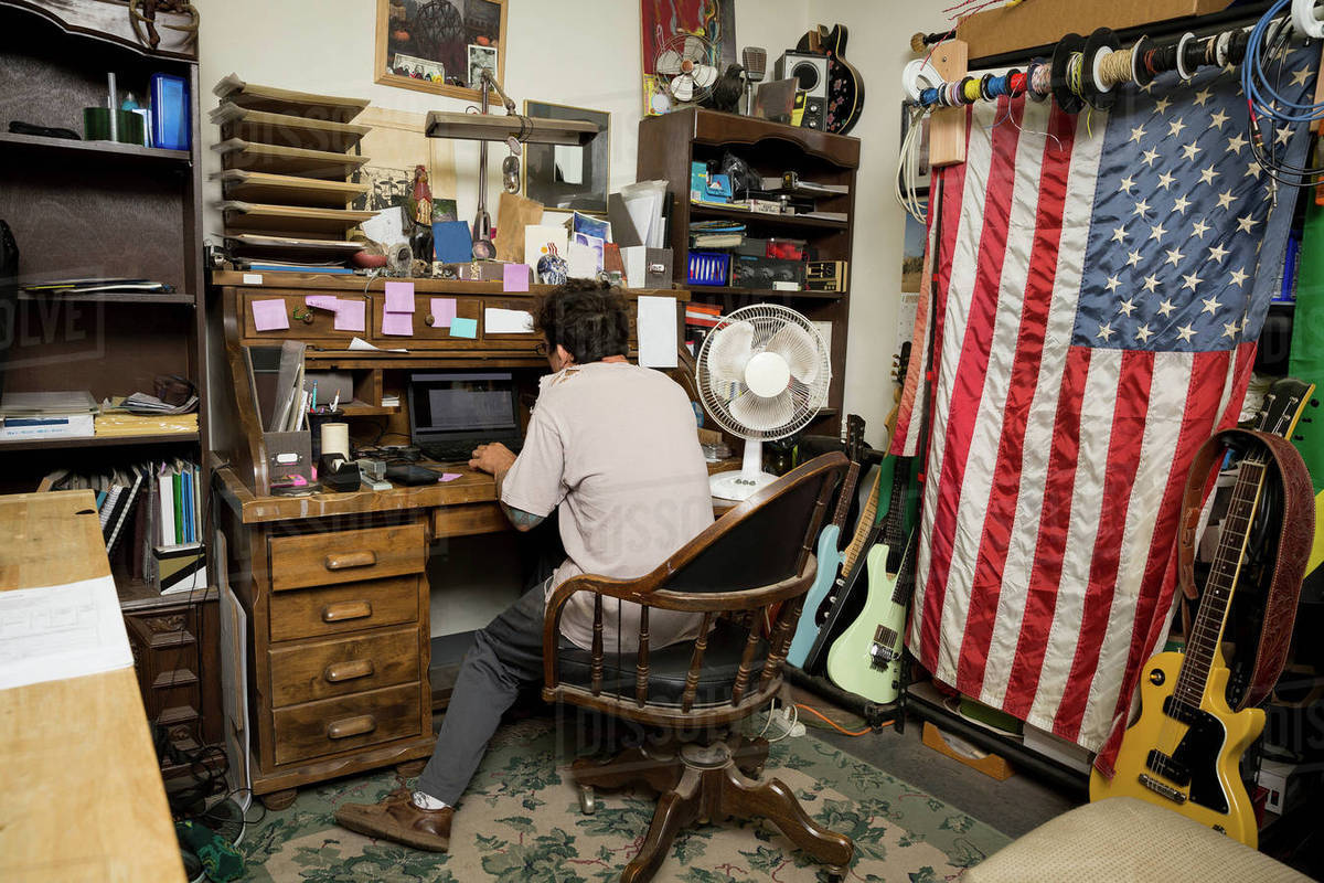 Man sitting at desk using laptop - Royalty-free Stock Photo | Dissolve