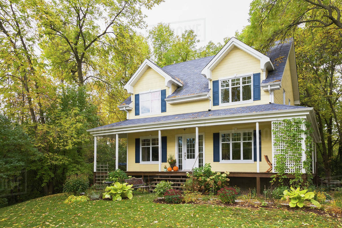 Yellow clapboard with blue and white trim cottage style home facade in ...