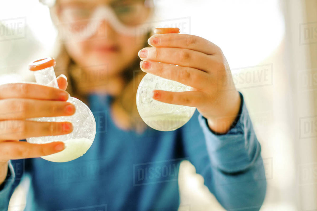 Girl doing science experiment, holding flasks of liquid - Royalty-free ...