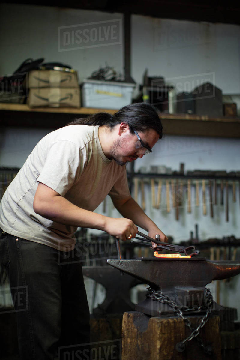 Male metalsmith shaping red hot metal on workshop anvil - Royalty-free ...