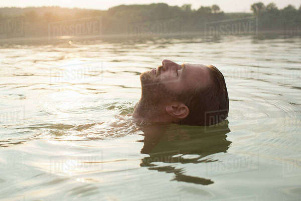 Man relaxing, floating in river - Stock Photo - Dissolve