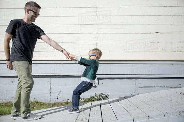 Boy pulling father up wooden ramp - Stock Photo - Dissolve