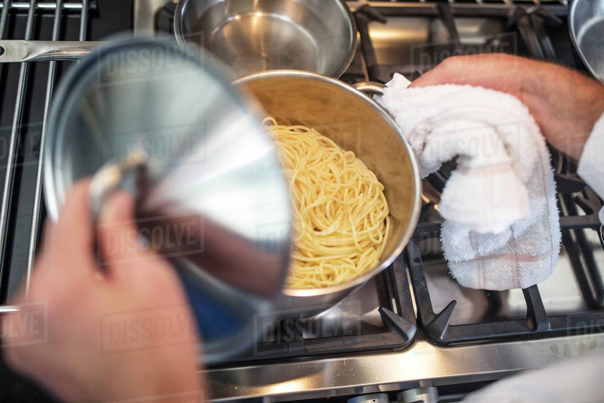 Chef lifting lid on pan of spaghetti on stove, elevated view - Royalty ...
