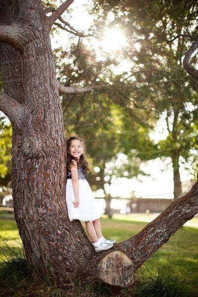 Portrait of girl standing on tree trunk - Stock Photo - Dissolve