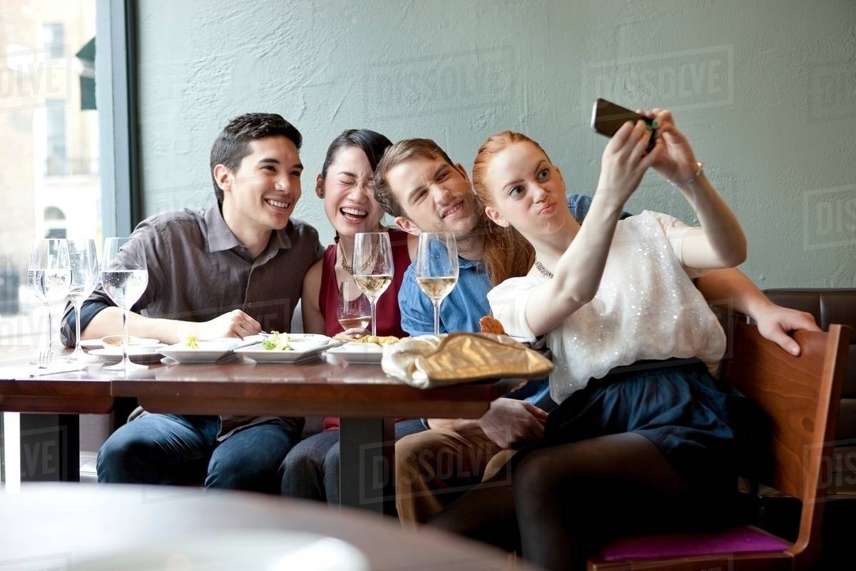 Four friends photographing themselves in restaurant - Stock Photo ...