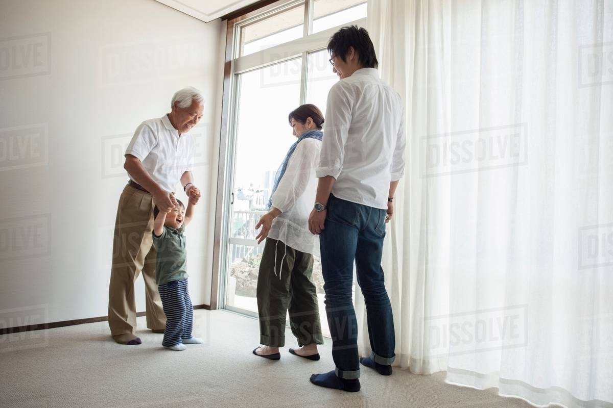 Three generation family standing by window - Stock Photo - Dissolve