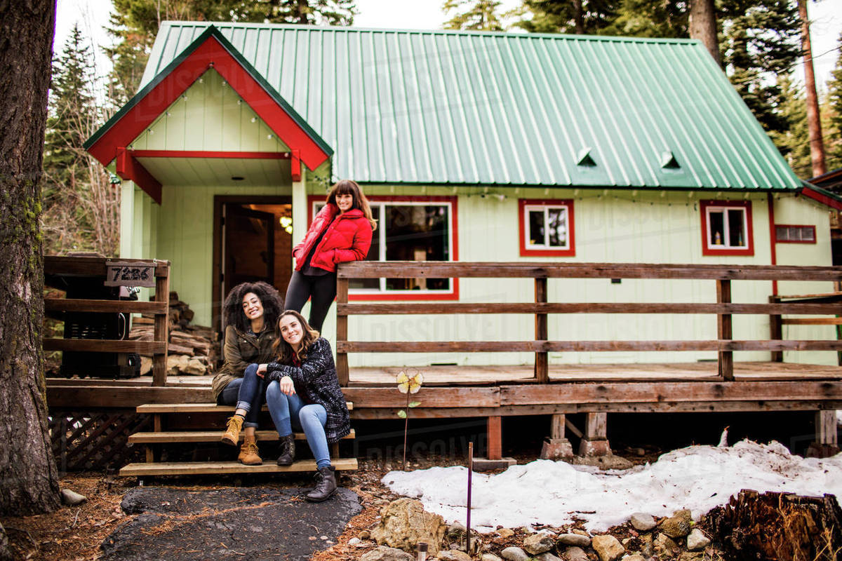 Portrait of three friends in front of cabin - Stock Photo - Dissolve