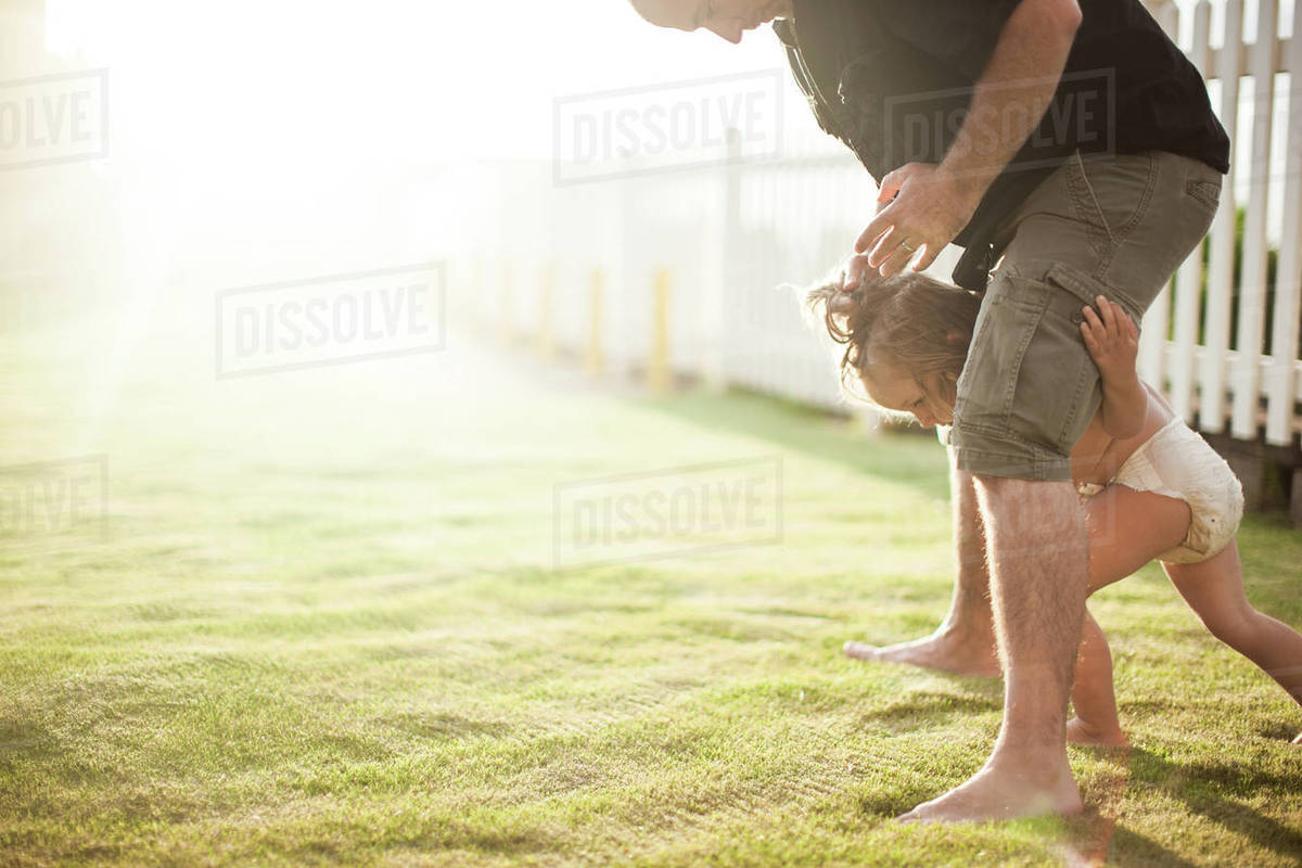 Father and son fooling around outdoors, young boy walking between ...