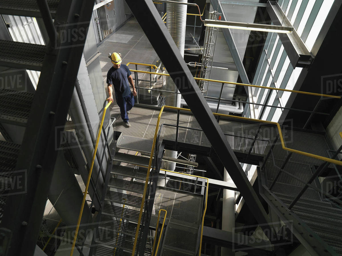 Worker climbing staircase in factory - Stock Photo - Dissolve