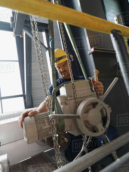 Worker operating machinery in factory - Stock Photo - Dissolve