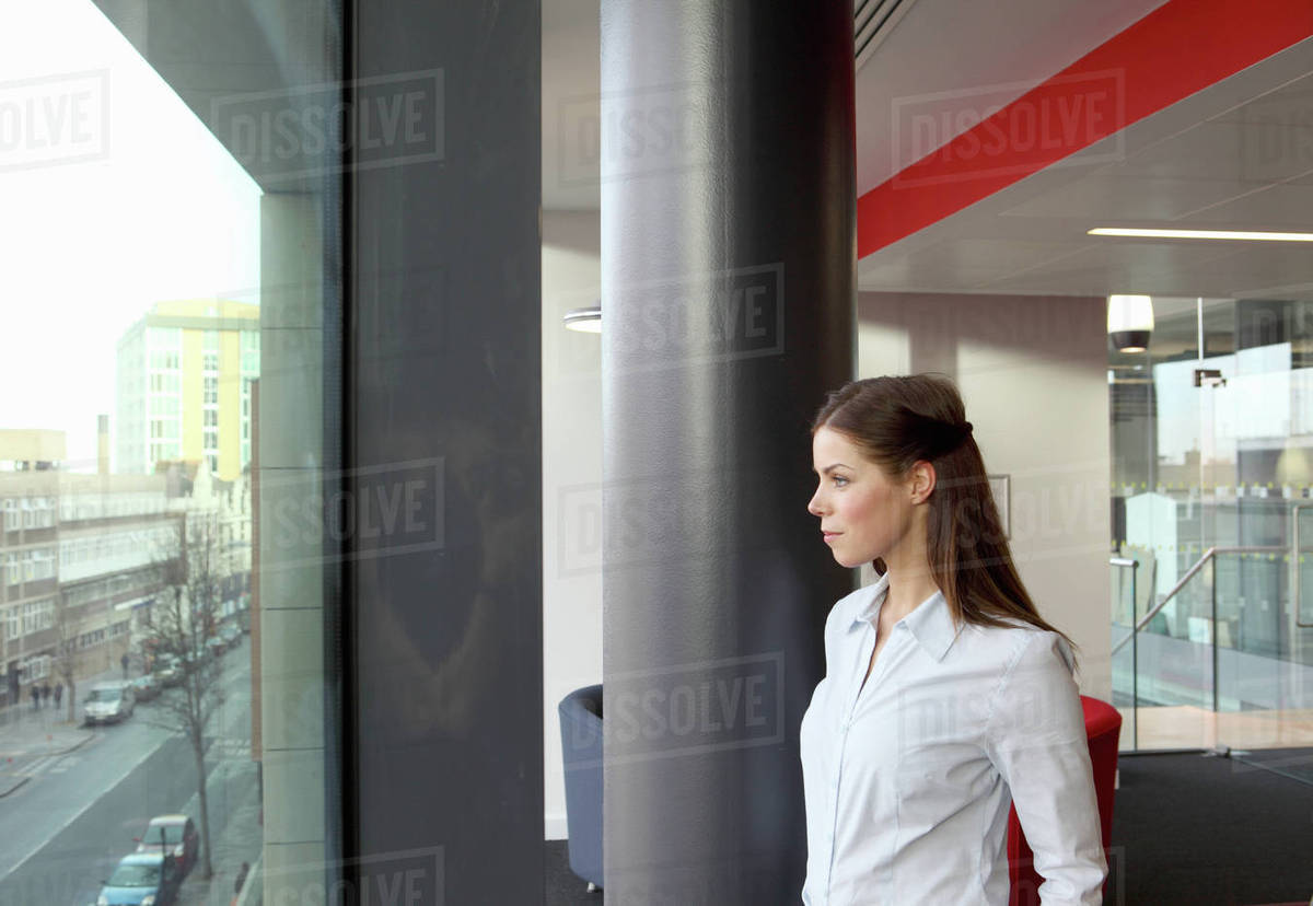 Businesswoman looking out office window - Stock Photo - Dissolve