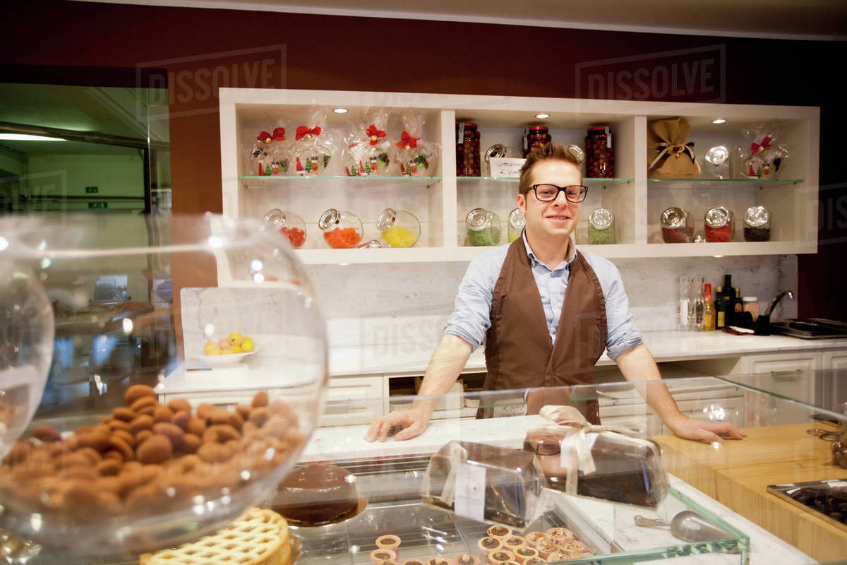 Cashier smiling behind bakery counter - Stock Photo - Dissolve