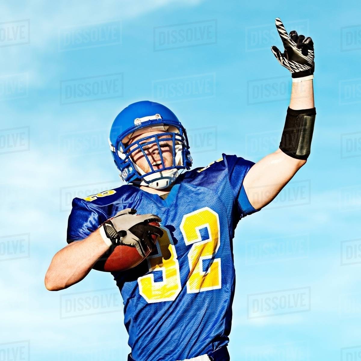 American footballer holding ball with arm raised - Stock Photo - Dissolve