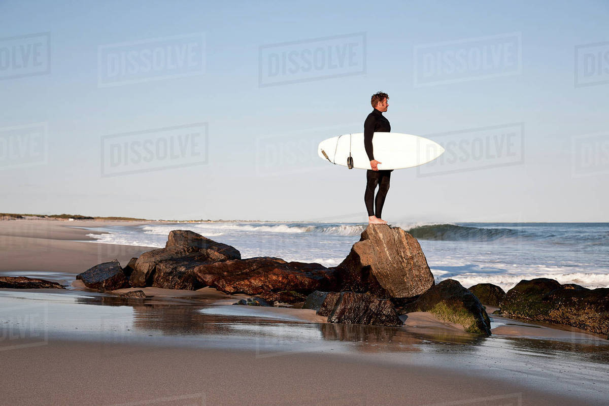 Surfer standing on rocks - Royalty-free Stock Photo | Dissolve