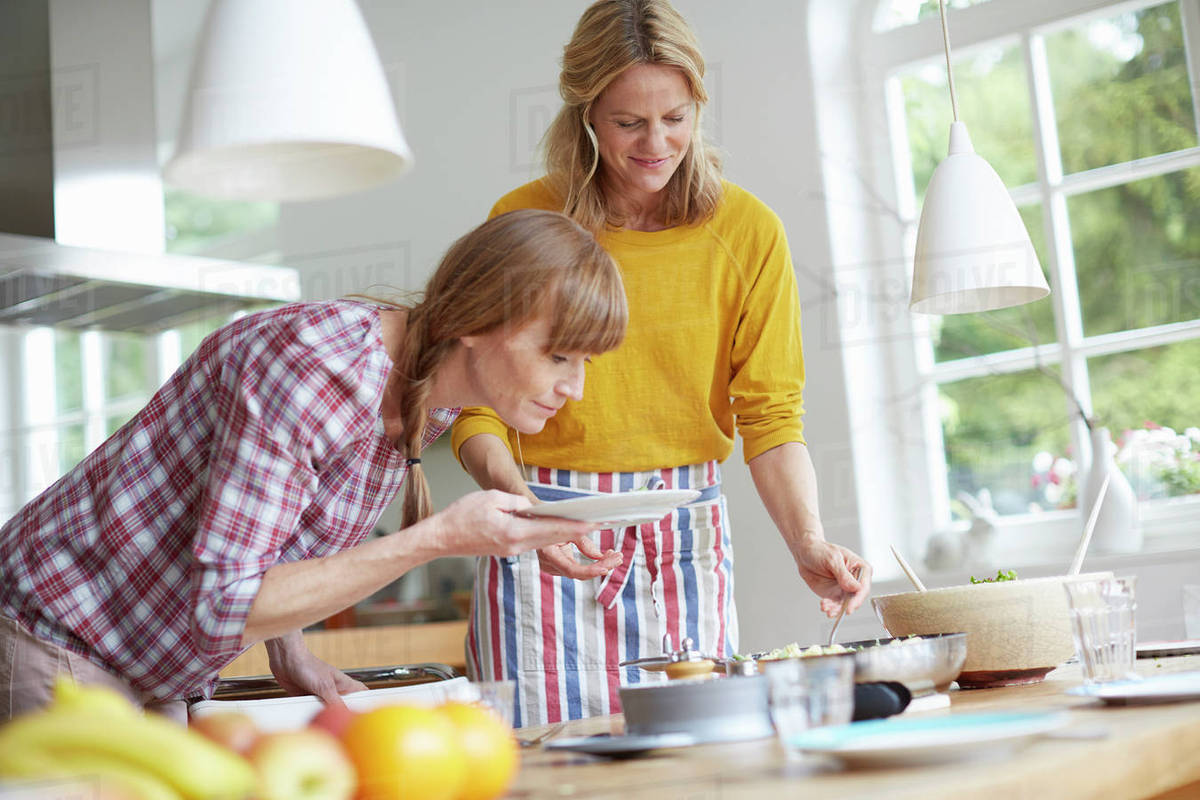 Woman serving meal at dining table - Stock Photo - Dissolve