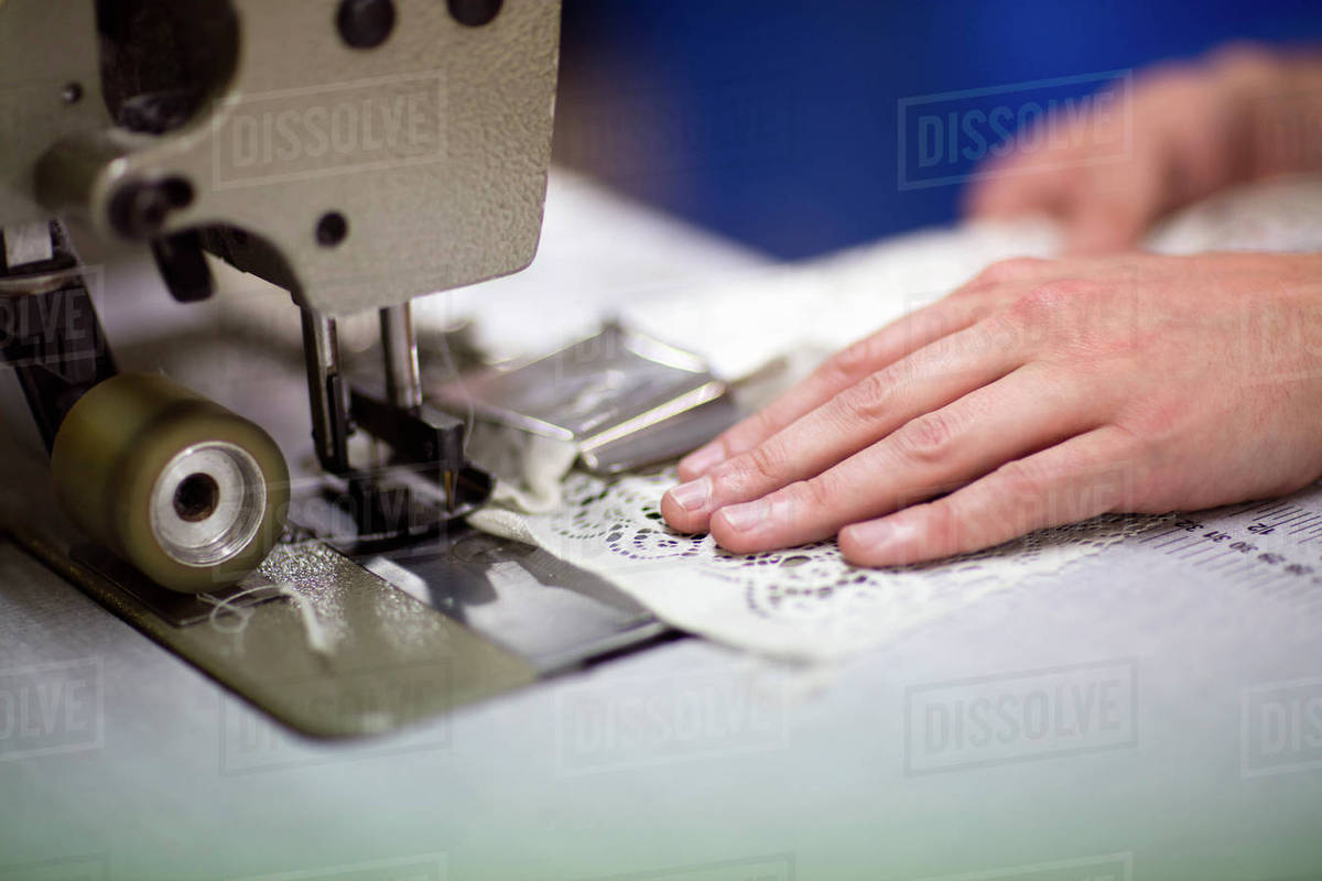 Hands of male textile designer using sewing machine in old textile mill ...