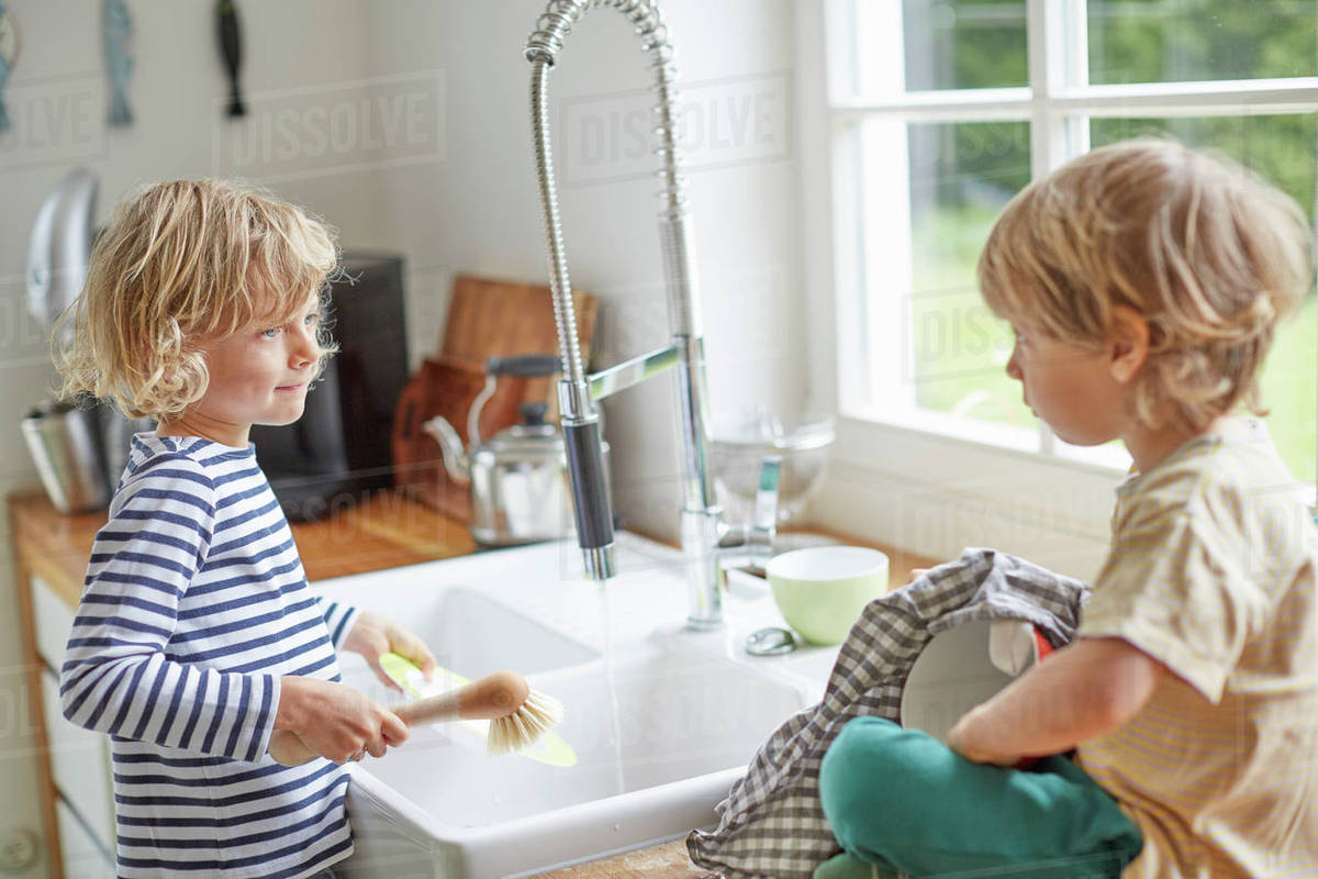 Two young brothers doing washing up - Stock Photo - Dissolve